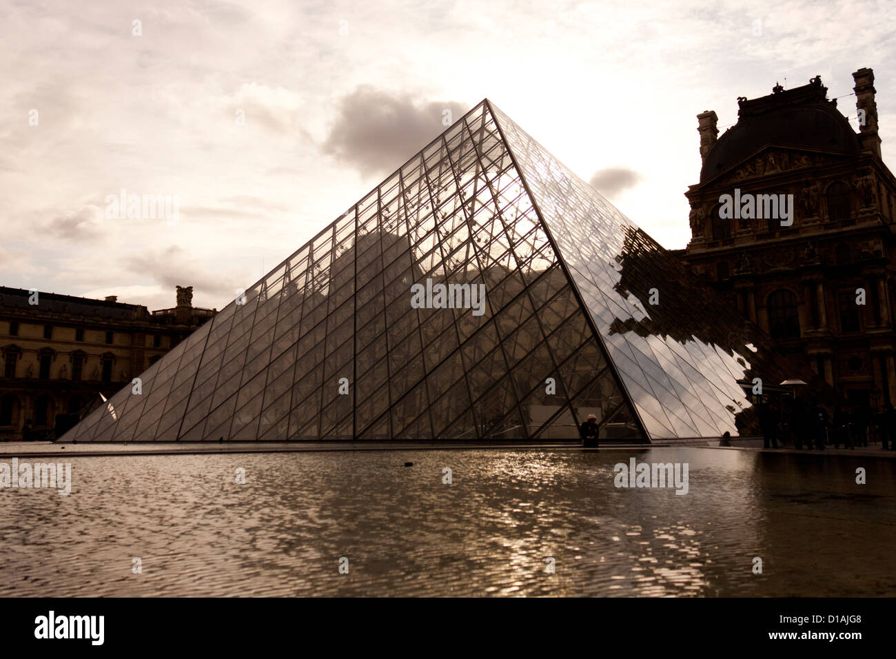 The Louvre glass pyramid and yellow sun reflection in water feature ...