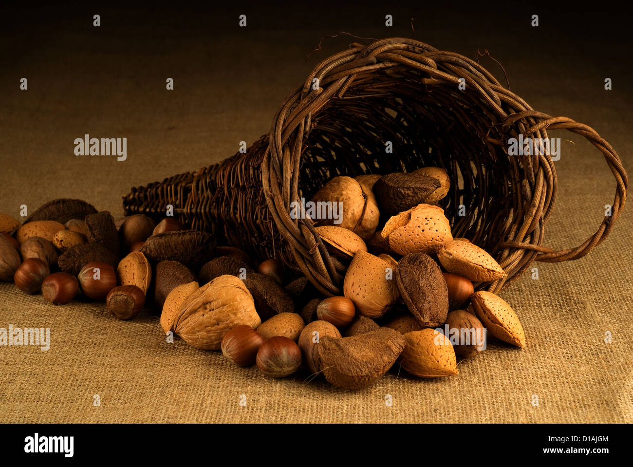 An assortment of nuts overflowing a basket on hesian background Stock ...