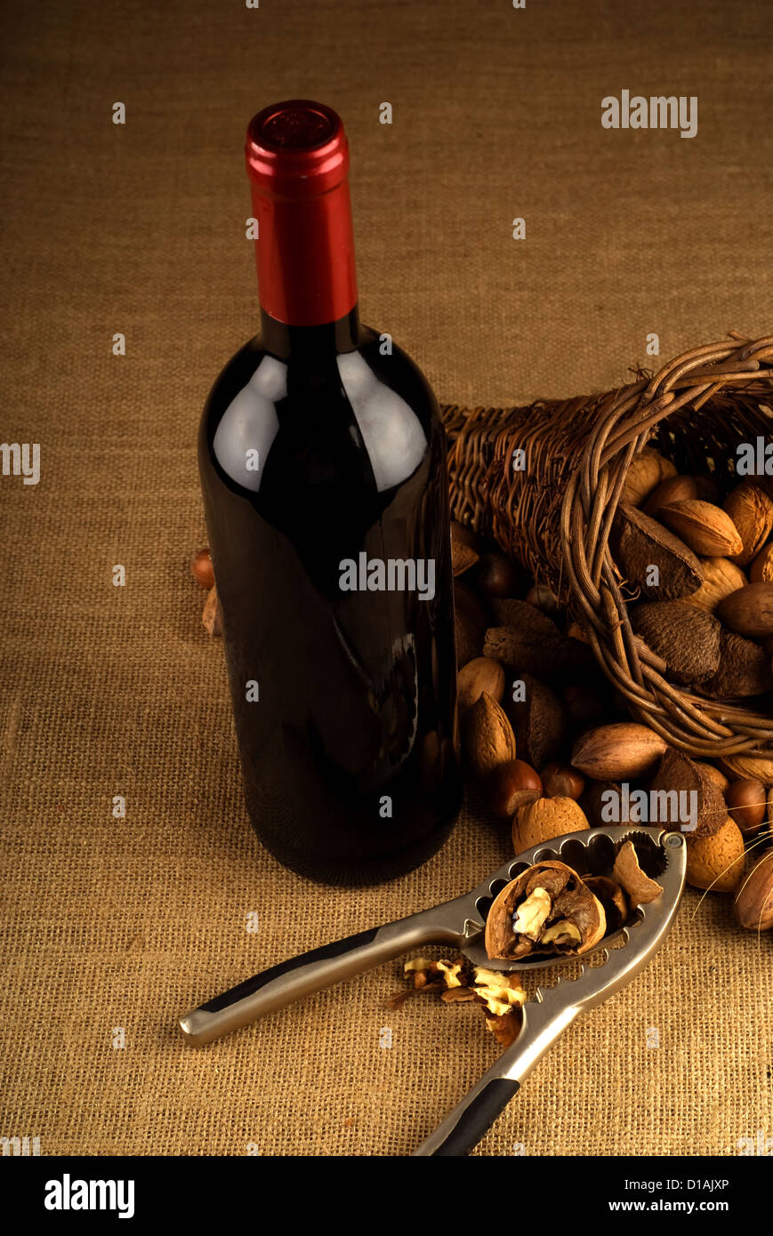 Assortment of nuts in basket with red wine bottle and nutcracker on ...
