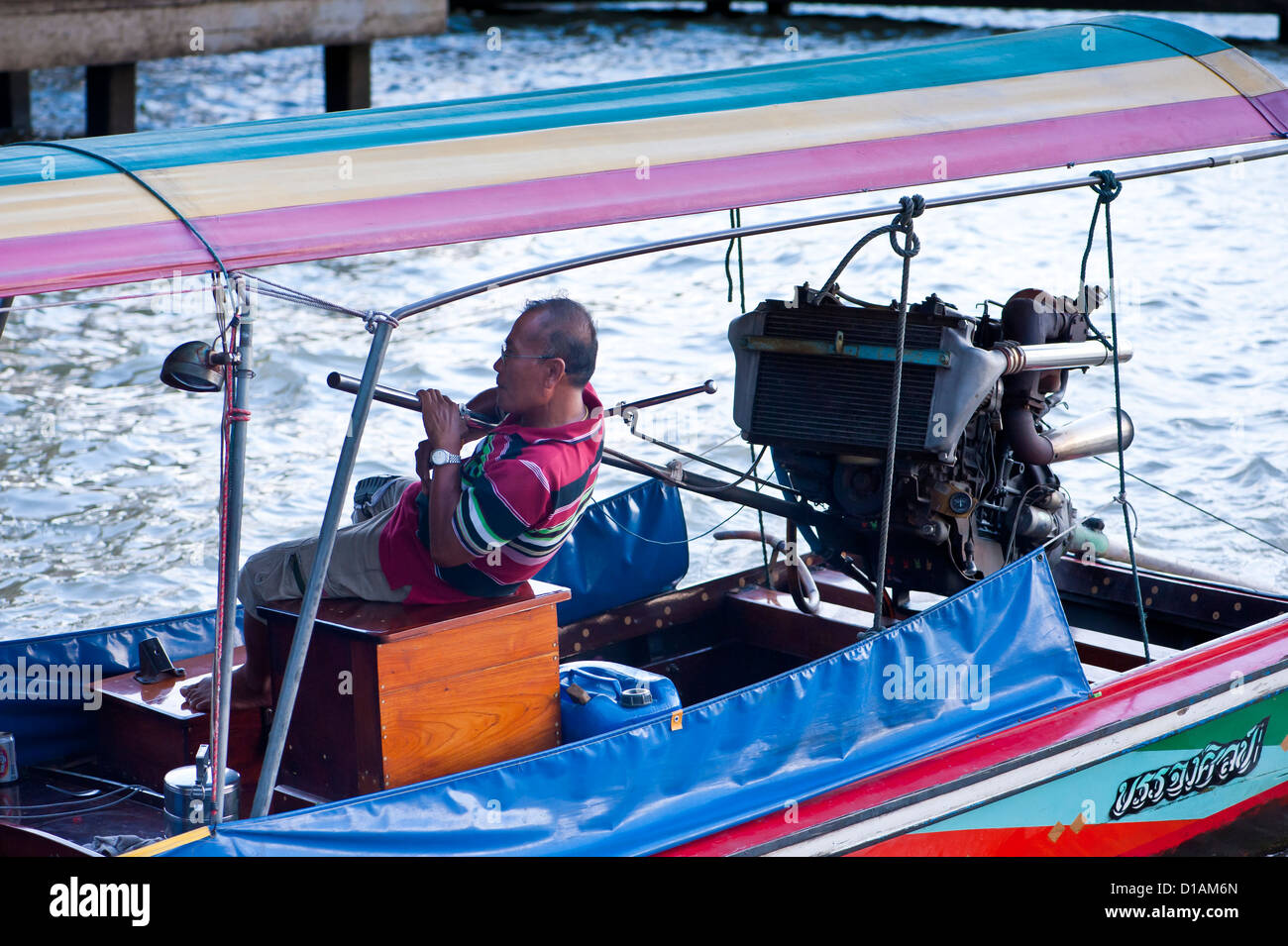 A Thai man holds the long tiller arm on a long tail boat, Bangkok Stock ...