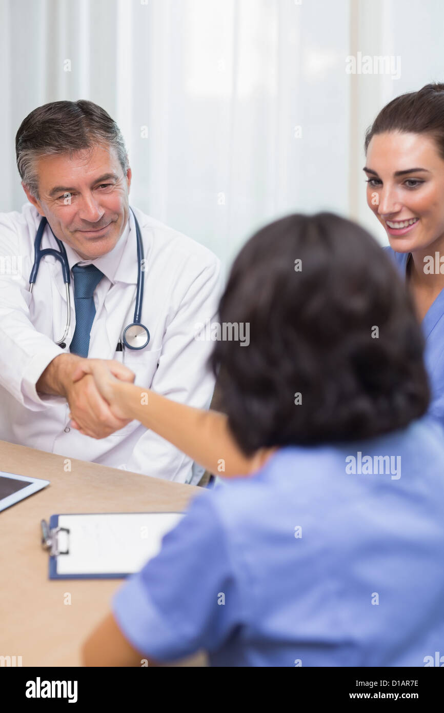 Smiling doctor shaking nurses hand Stock Photo - Alamy