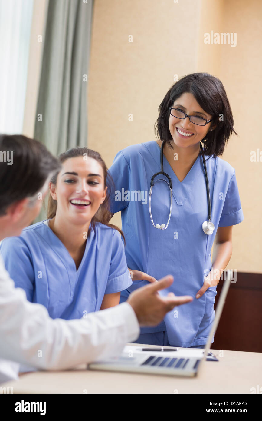 Nurses laughing with doctor using laptop Stock Photo - Alamy