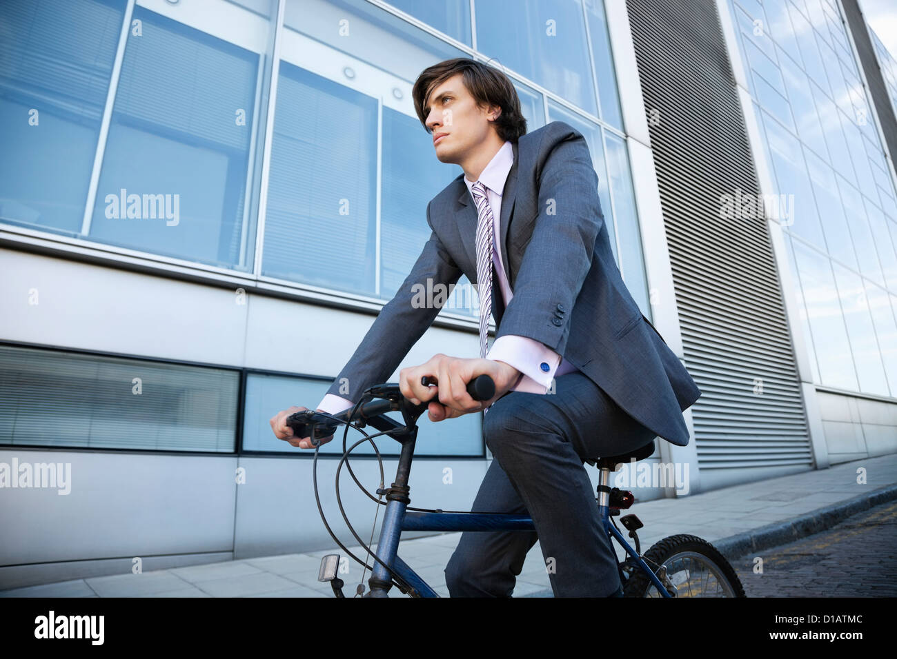 Low angle view young businessman riding bicycle by building Stock Photo ...