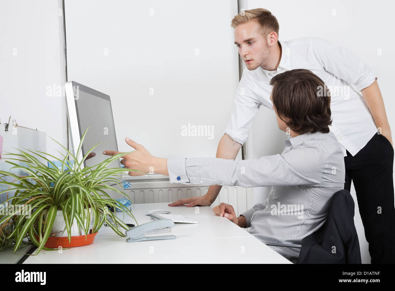 Businessman showing computer screen to coworker at desk Stock Photo - Alamy
