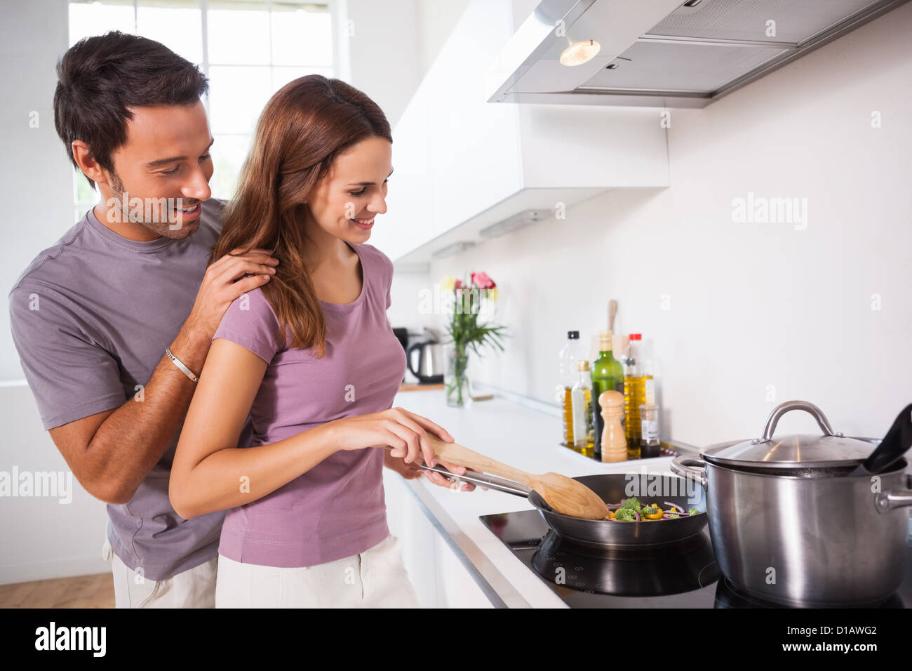 Woman making dinner with partner watching Stock Photo - Alamy