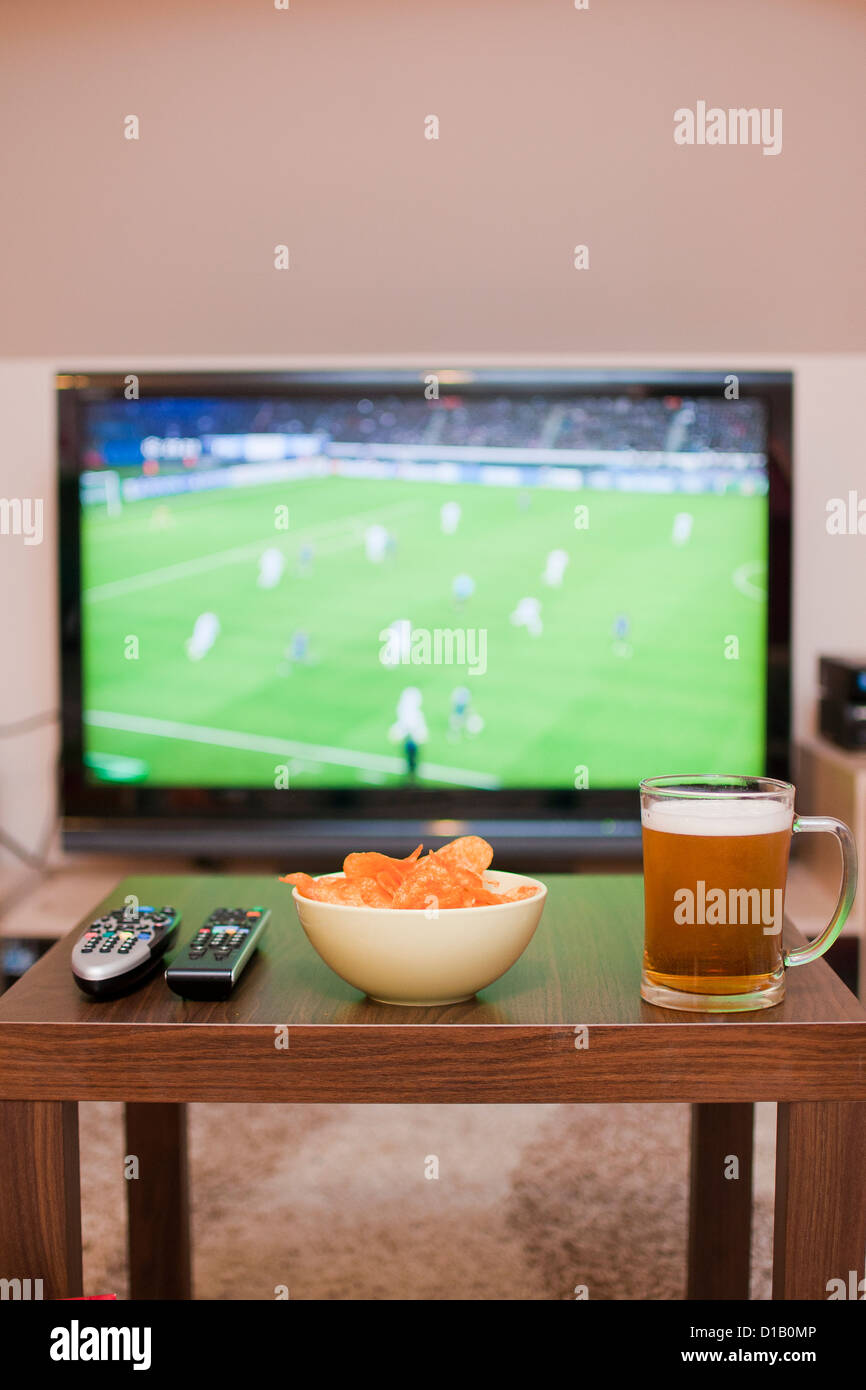 beer, chips and remote controls on the table (in the background TV ...