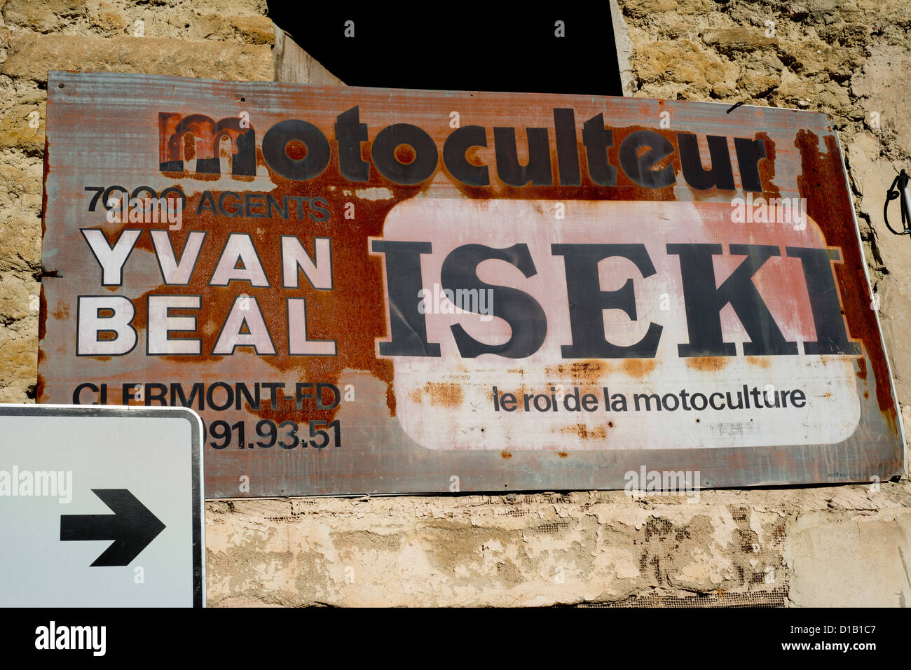 A n old French sign over a garage for a type of mower with an arrow in ...