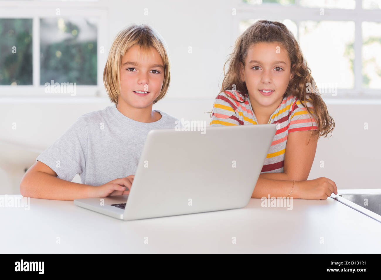 Two children looking at the camera with laptop Stock Photo - Alamy