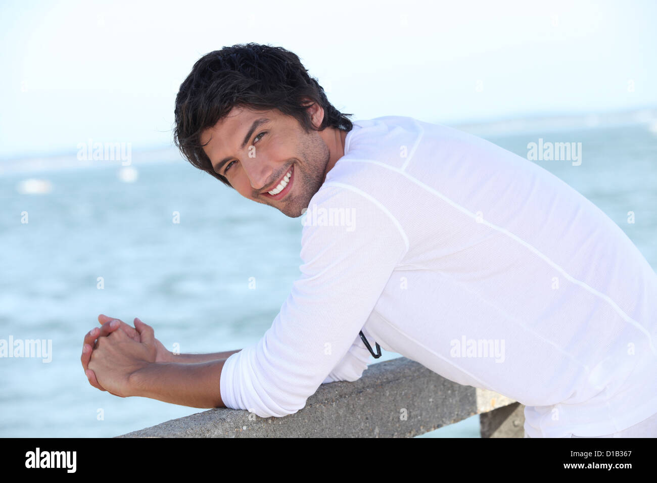 Man leaning on barrier by the sea Stock Photo - Alamy