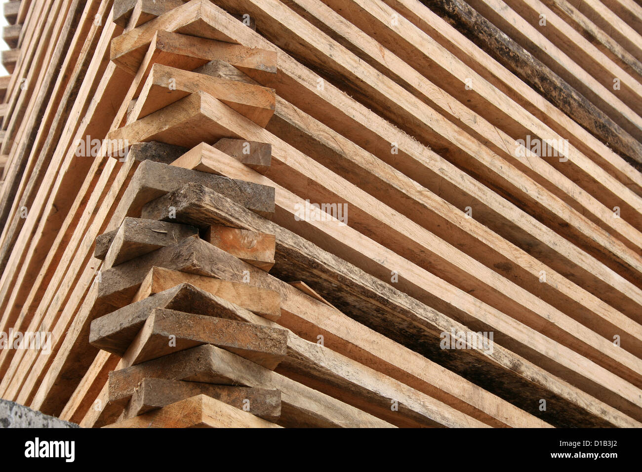 Freshly cut boards are stacked in a triangle pattern in the outdoor ...