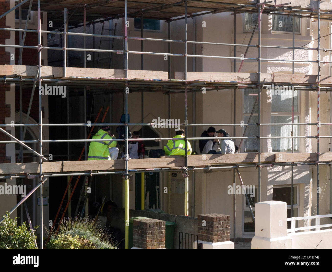 builders take a tea break sat amongst scaffolding on residential ...