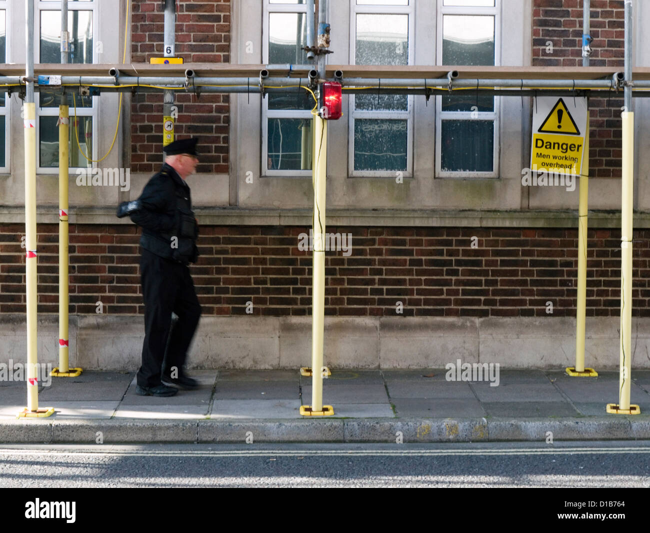 traffic warden walking along pavement below scaffolding Stock Photo - Alamy