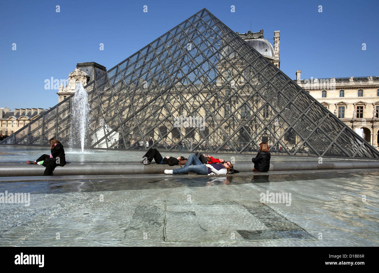 Paris, France, people bask in front of the glass pyramid at the Louvre ...
