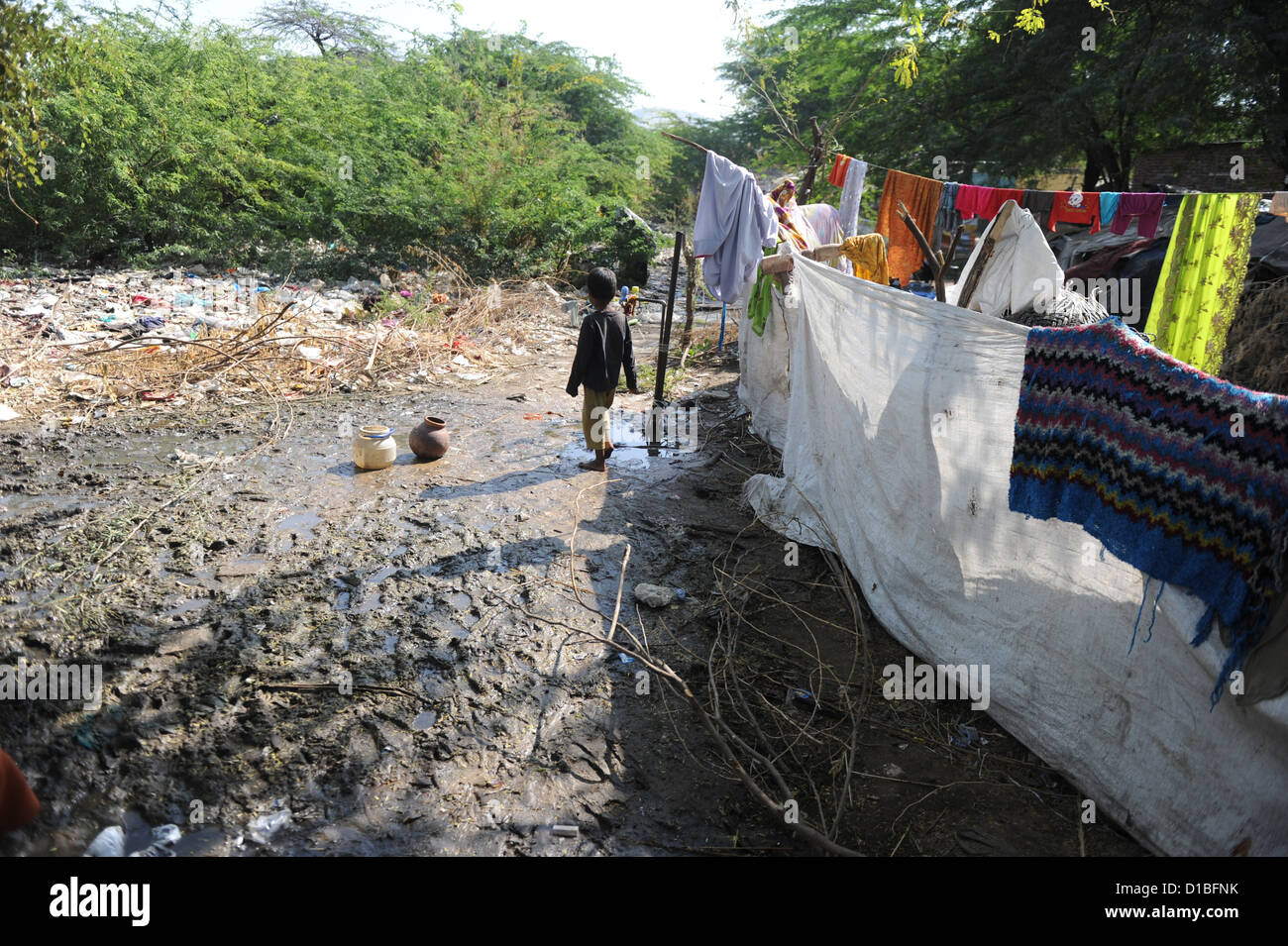 An Indian boy walks through mud and waste in a slum in Jaipur, India ...