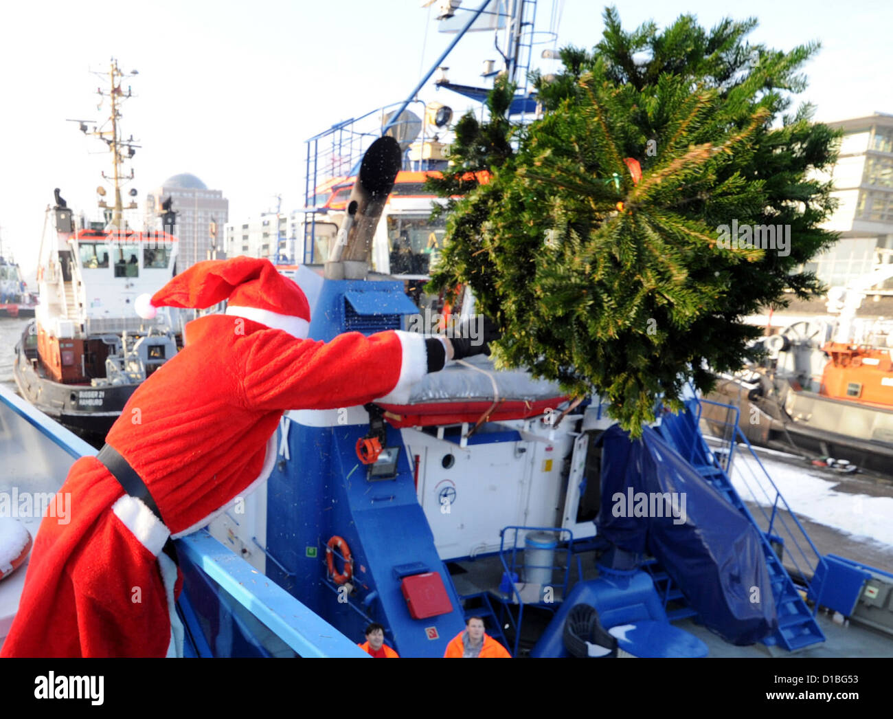 A man dressed as Santa Claus throws a Christmas tree onto a ship in the ...