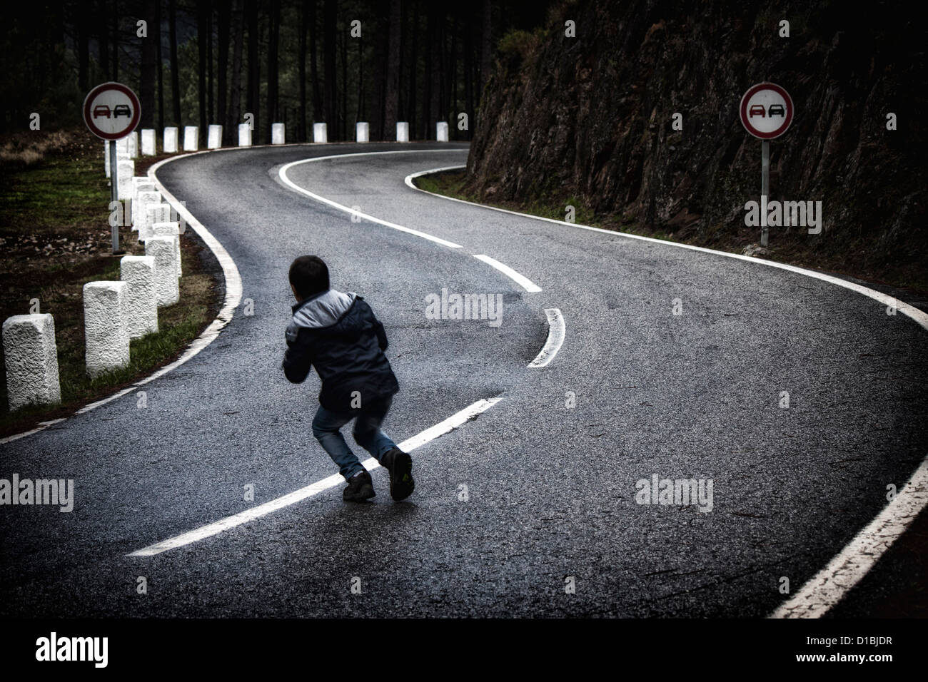 Twisted mountain road with kid running on it Stock Photo - Alamy
