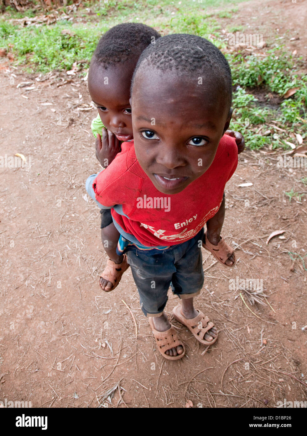 Small 4 year old African boy caring his 2 year old sister on his back ...