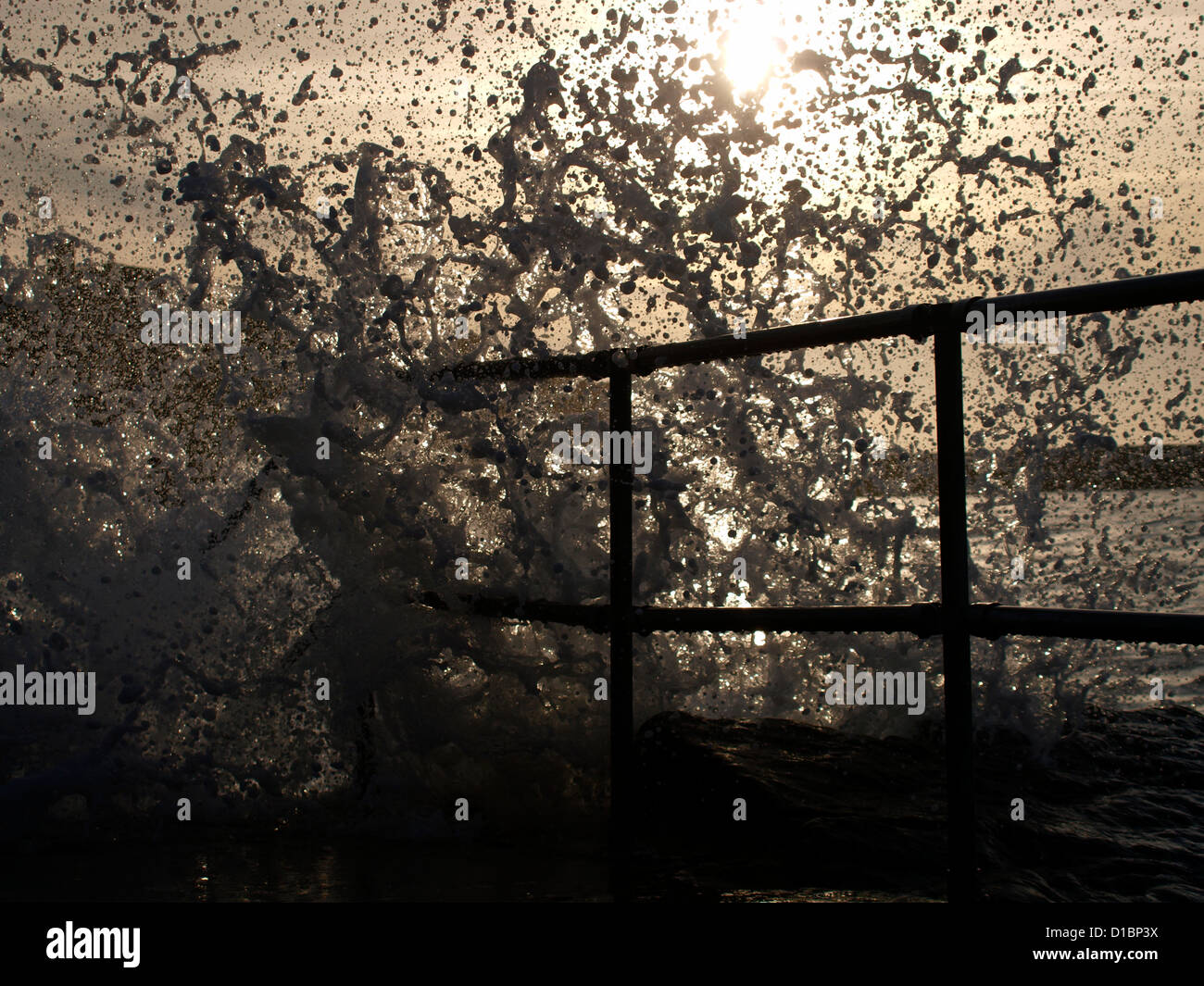 Wave hitting railings at the seaside at sunset, Bude, Cornwall, UK ...