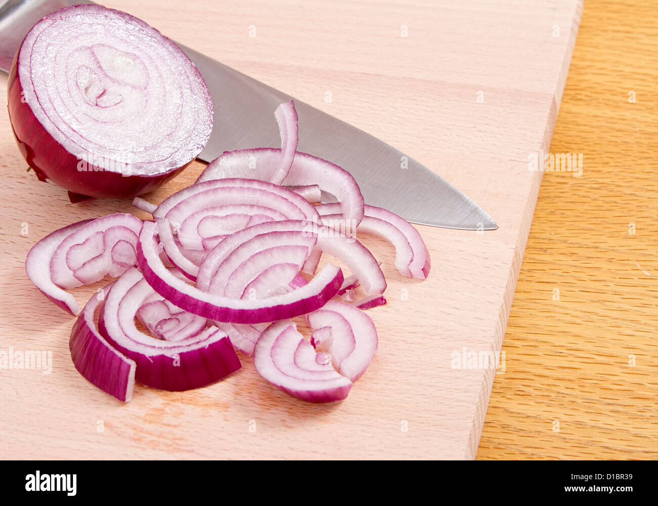 Red onion half with chopped slices and knife on wooden block Stock ...