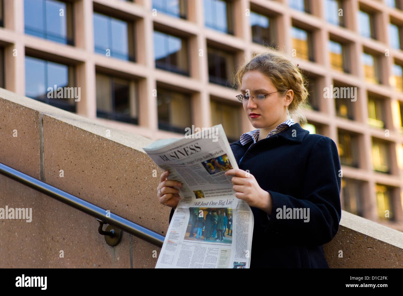 Woman reading newspaper outside of office building Stock Photo - Alamy
