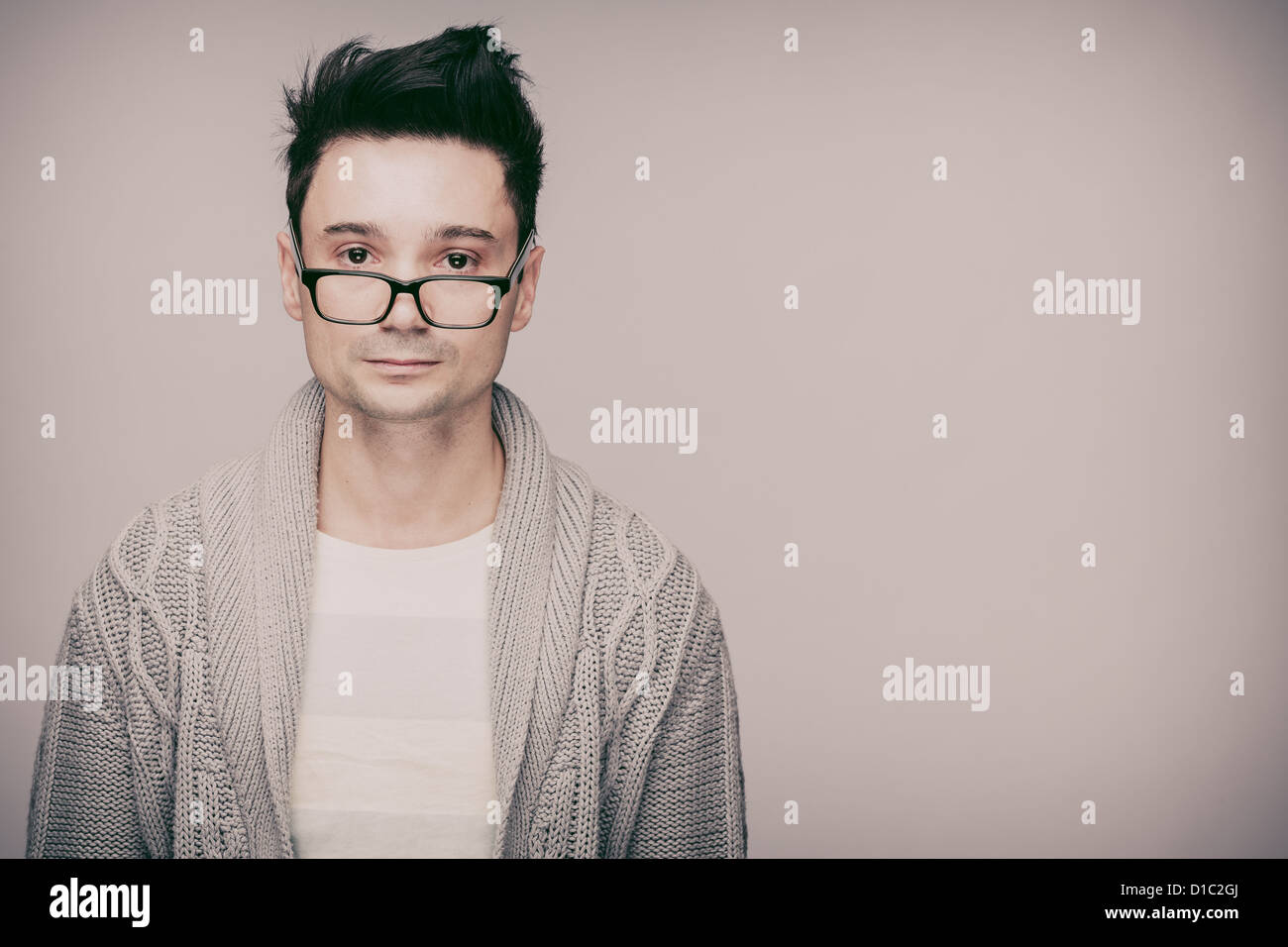 Unimpressed man stares over his glasses in grey cardigan and striped T ...