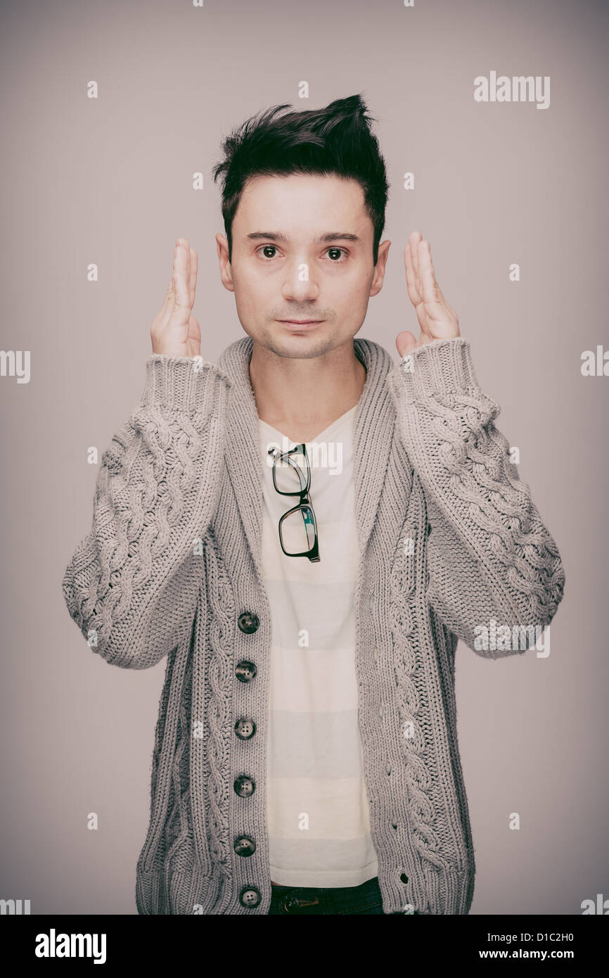 Man staring intensely with hands either side of face in grey cardigan ...