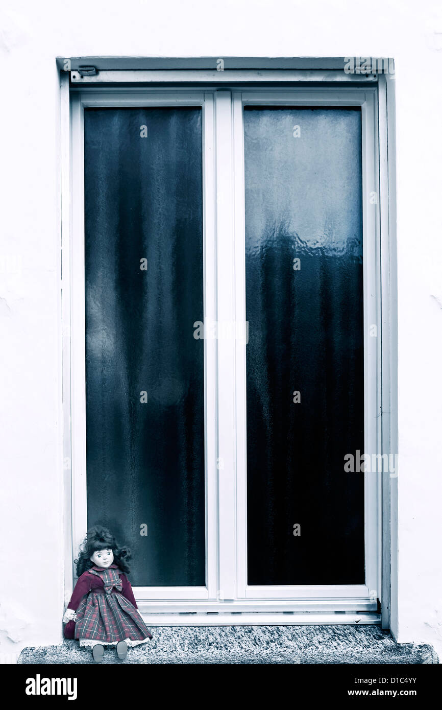 an old doll sitting on a window sill Stock Photo - Alamy