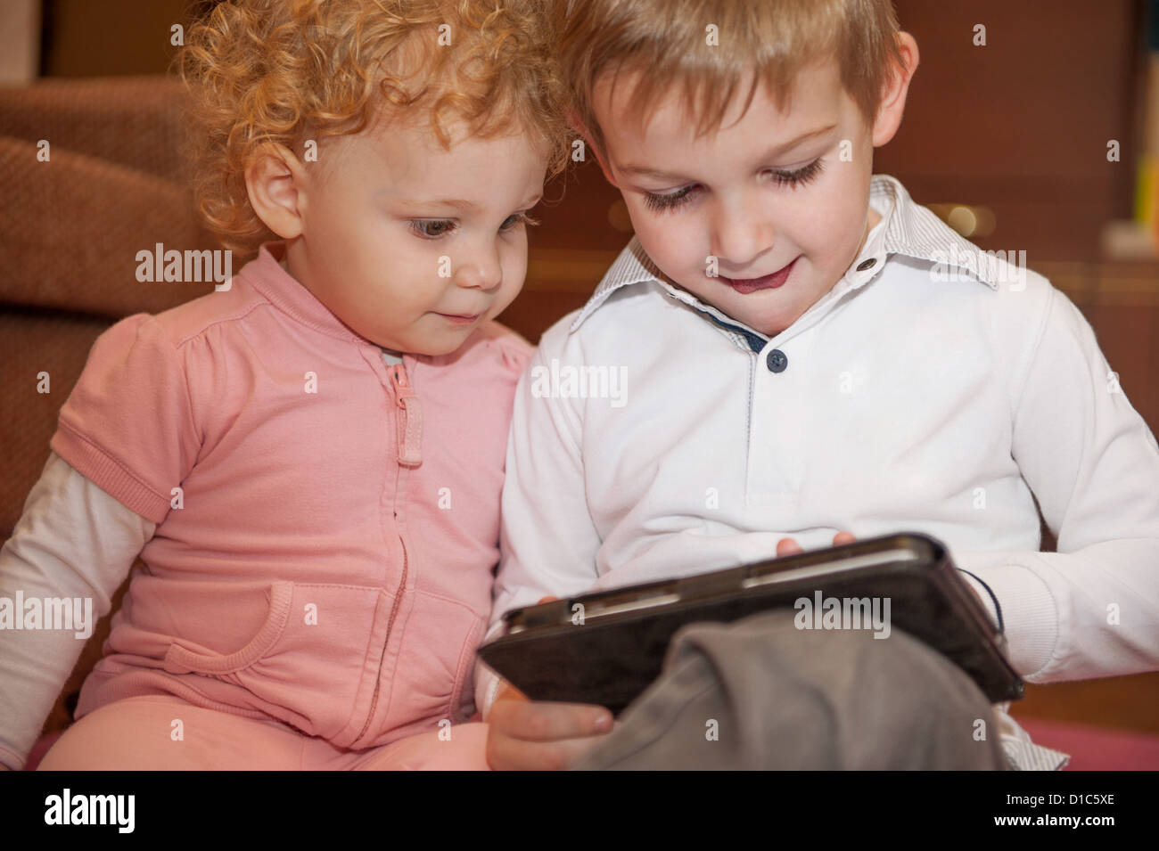 Two kids having fun with a digital tablet Stock Photo - Alamy