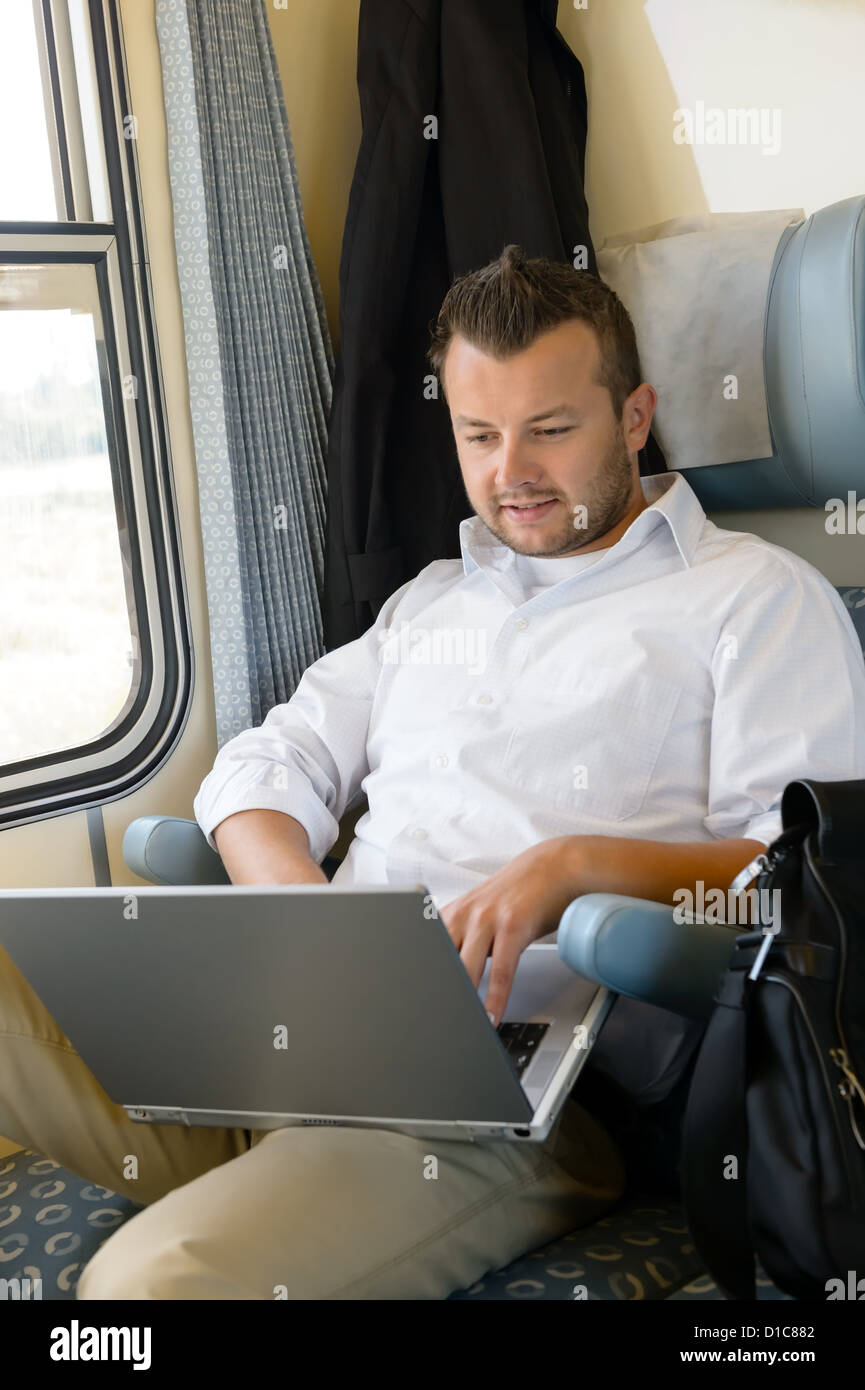 Man sitting in train using laptop computer commuting from work Stock ...