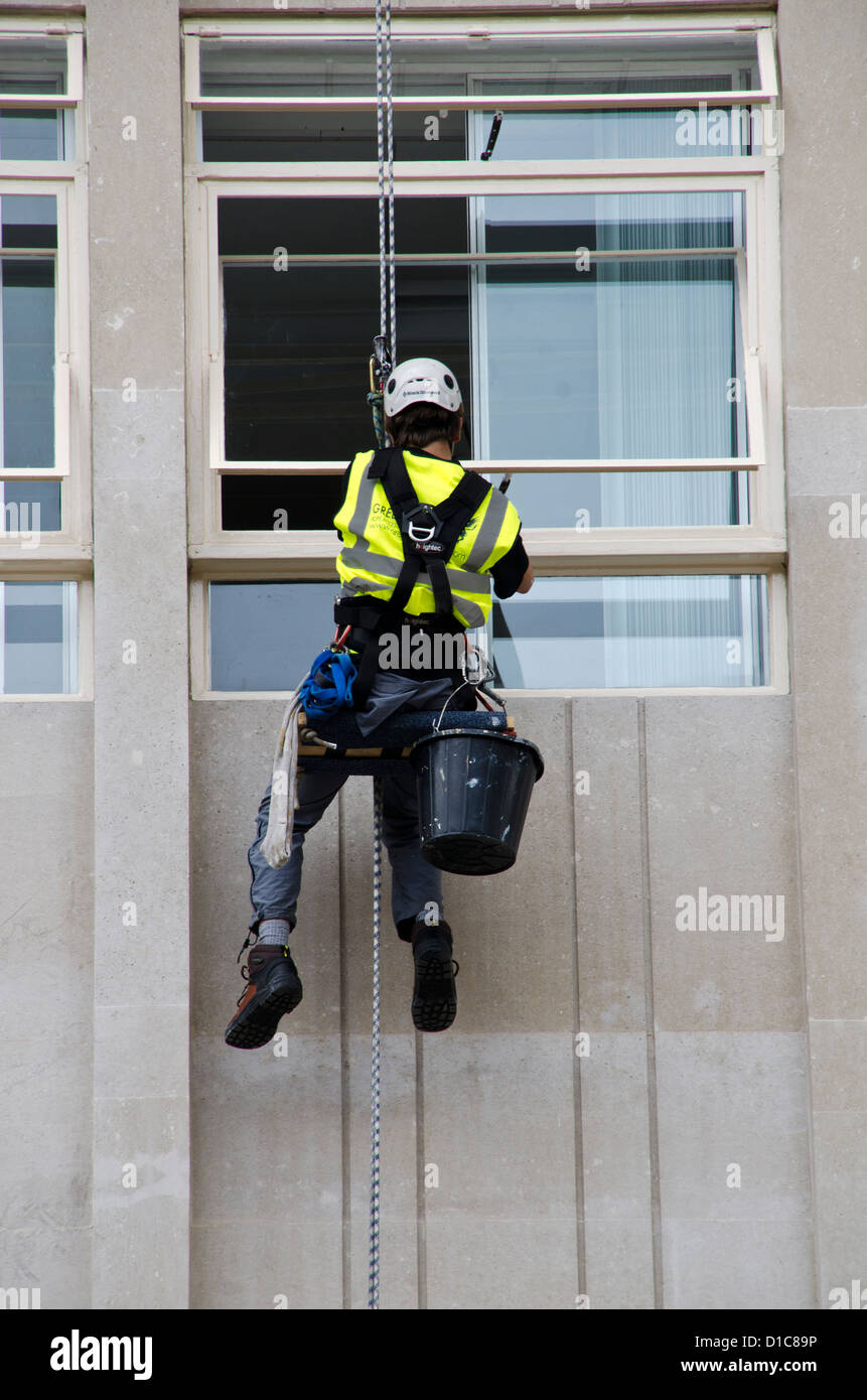 Worker hanging on the rope repairing the window Stock Photo - Alamy
