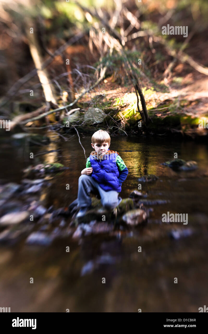 Little boy sitting on rock in the middle of a stream Stock Photo - Alamy