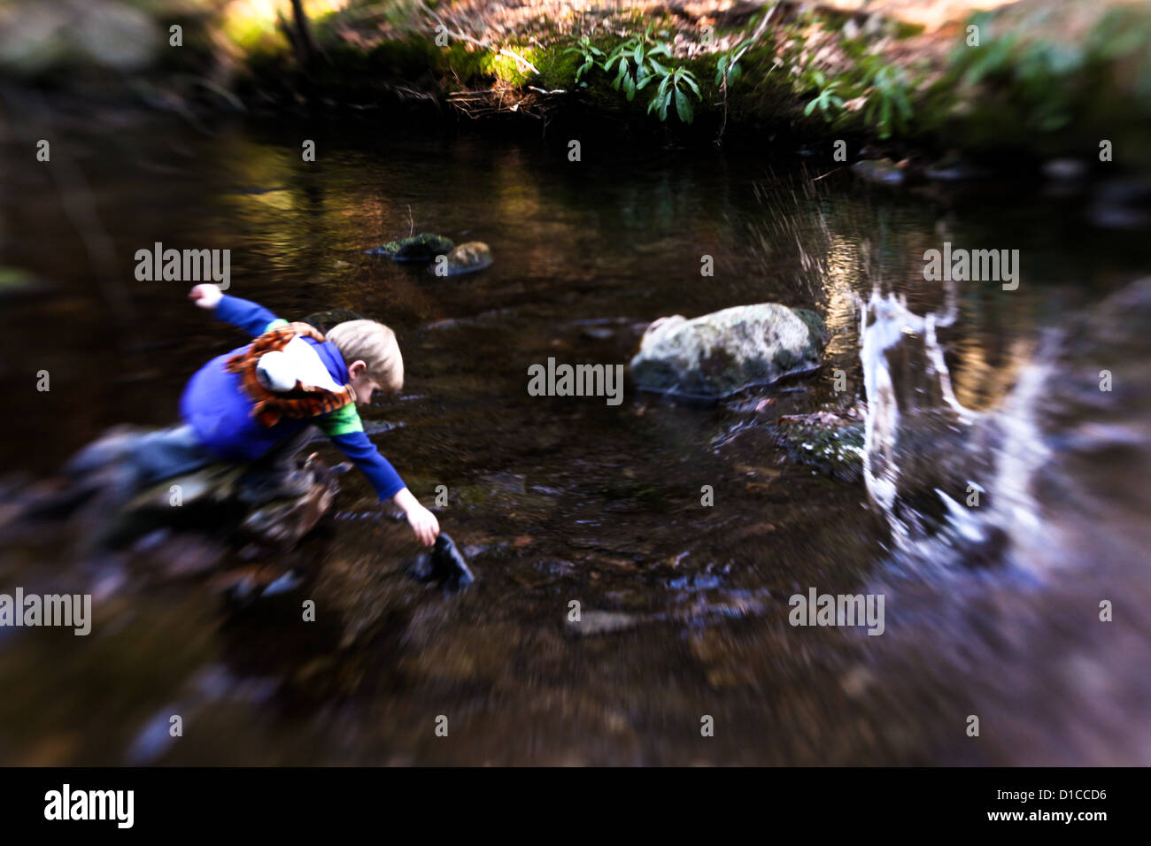 Little boy sitting on rock in the middle of a stream Stock Photo - Alamy