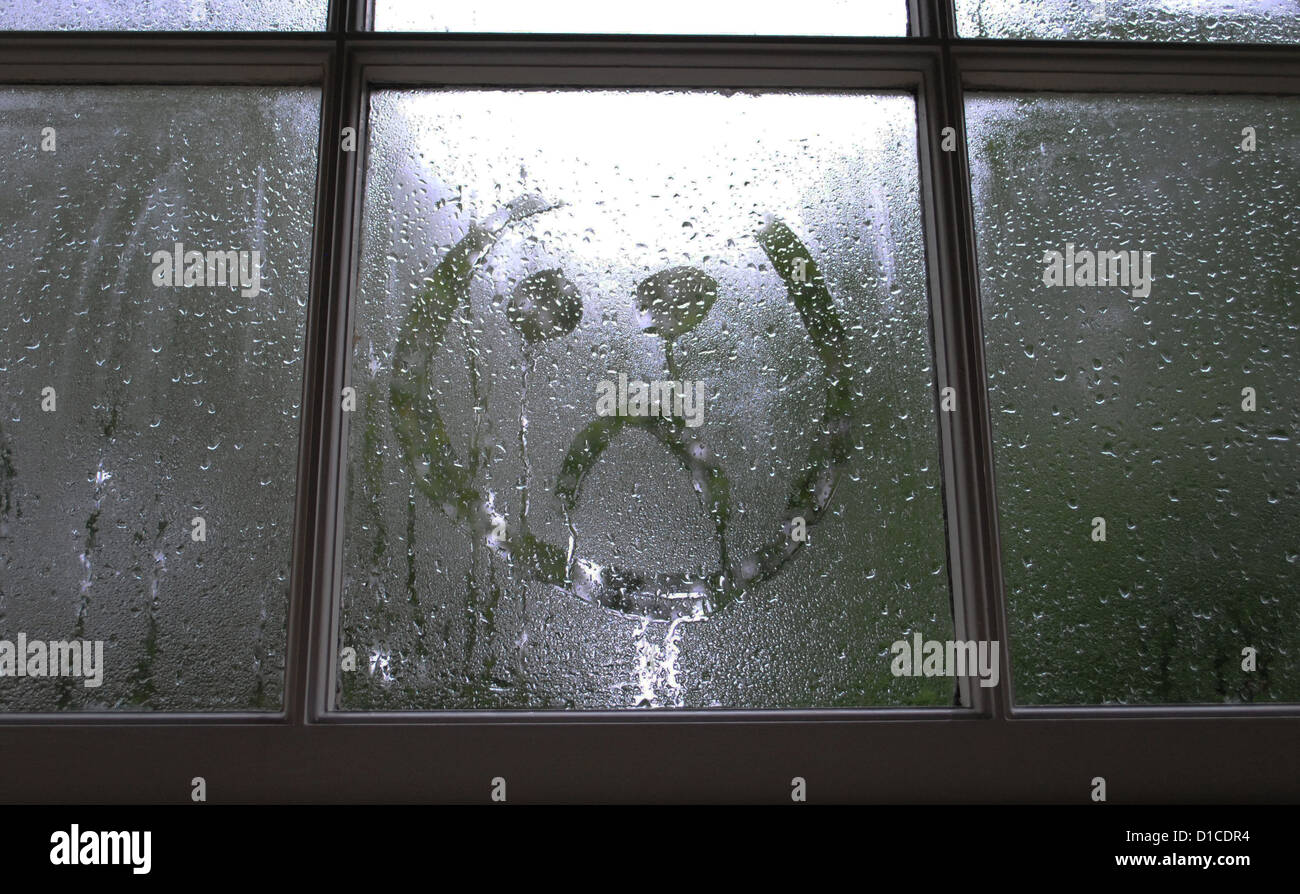 Sad face drawn in window condensation Stock Photo - Alamy
