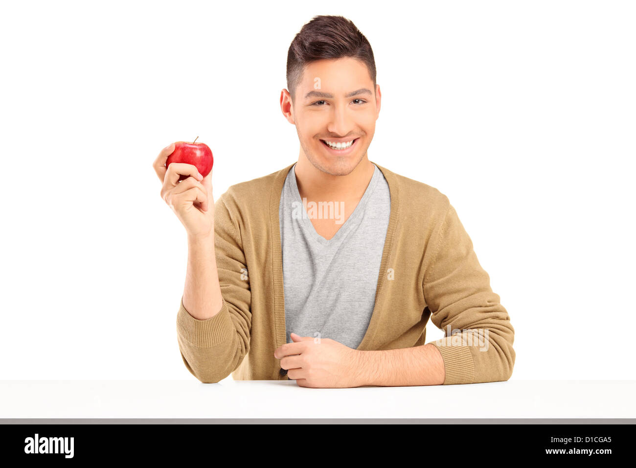 Handsome smiling guy holding a red apple and posing on a table isolated ...