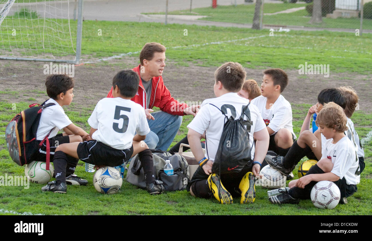 Coach discussing soccer game strategy with boys age 10 during a rest ...