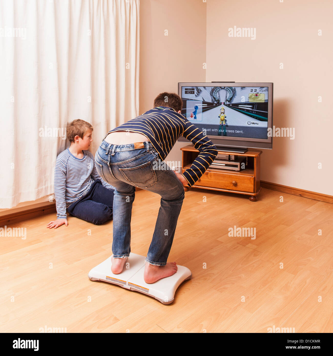 A 13 year old boy playing on a Nintendo Wii Fit board with brother ...