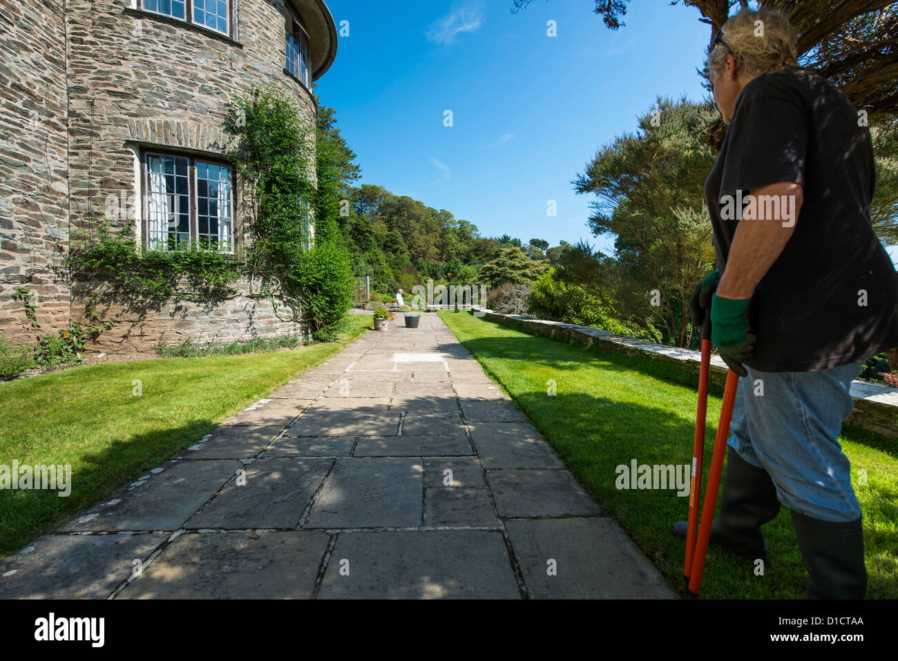 Kingswear, Devon, England. Country house with a lady trimming the grass ...
