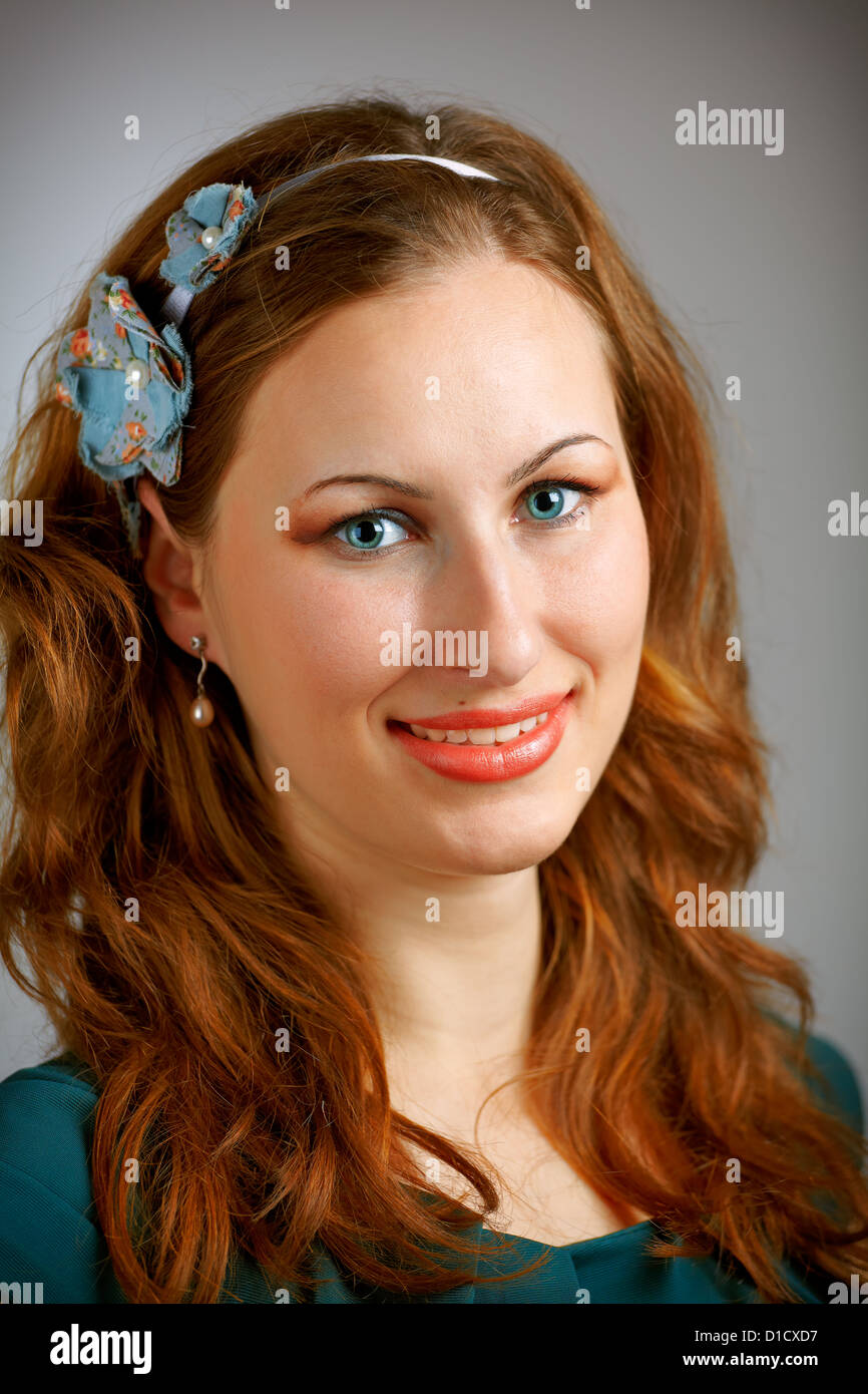 Studio portrait of a beautiful 20 year old redhead woman against gray ...
