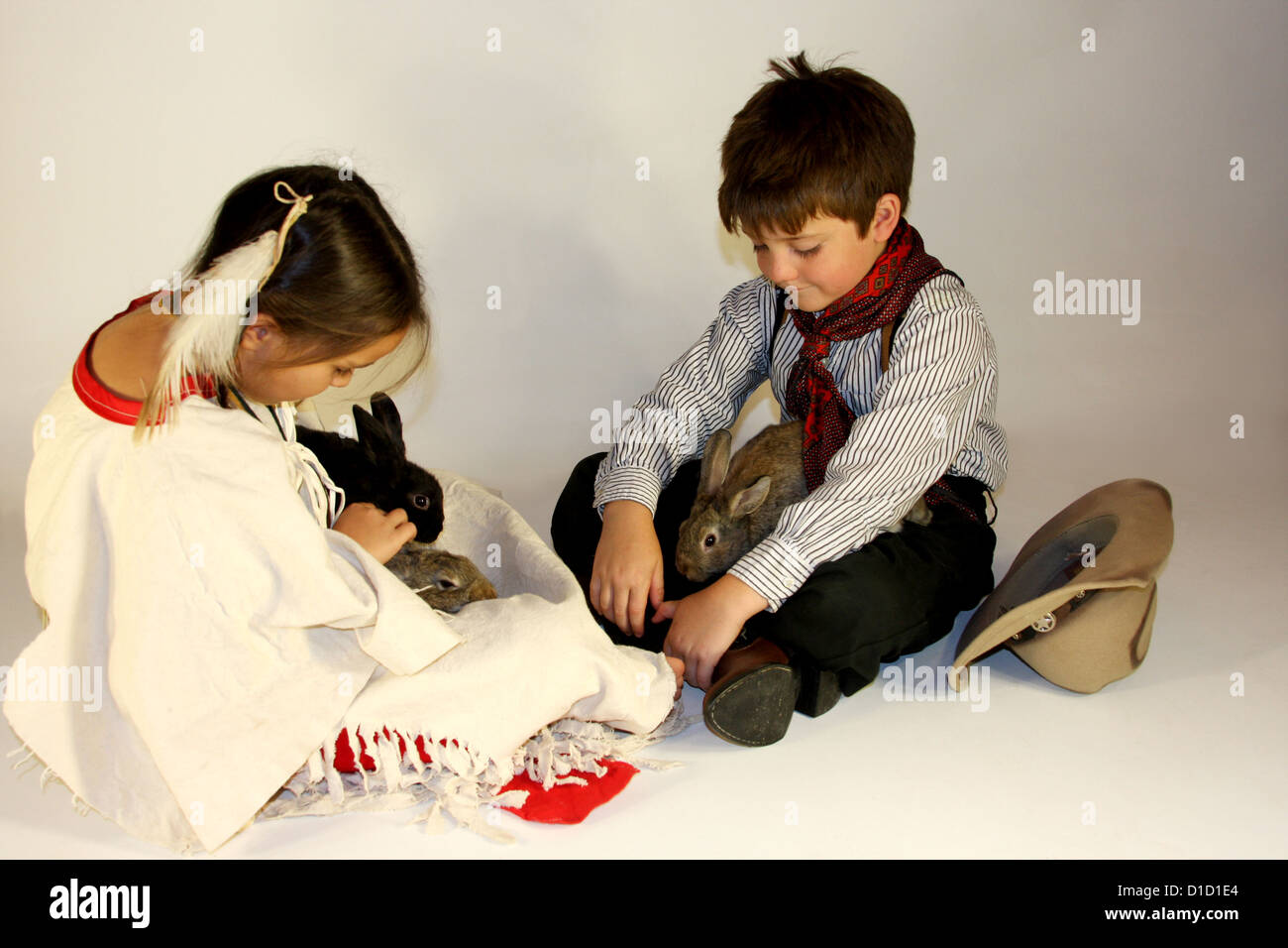 A Native American Indian girl and a cowboy child holding four bunny ...