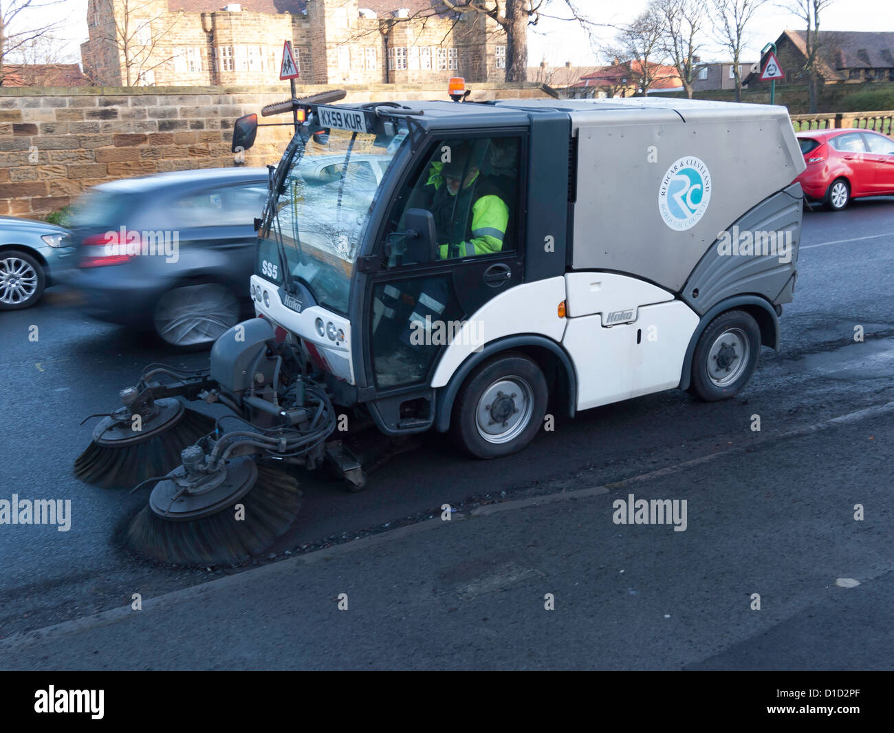 A small one man operated street sweeping machine working in an urban ...