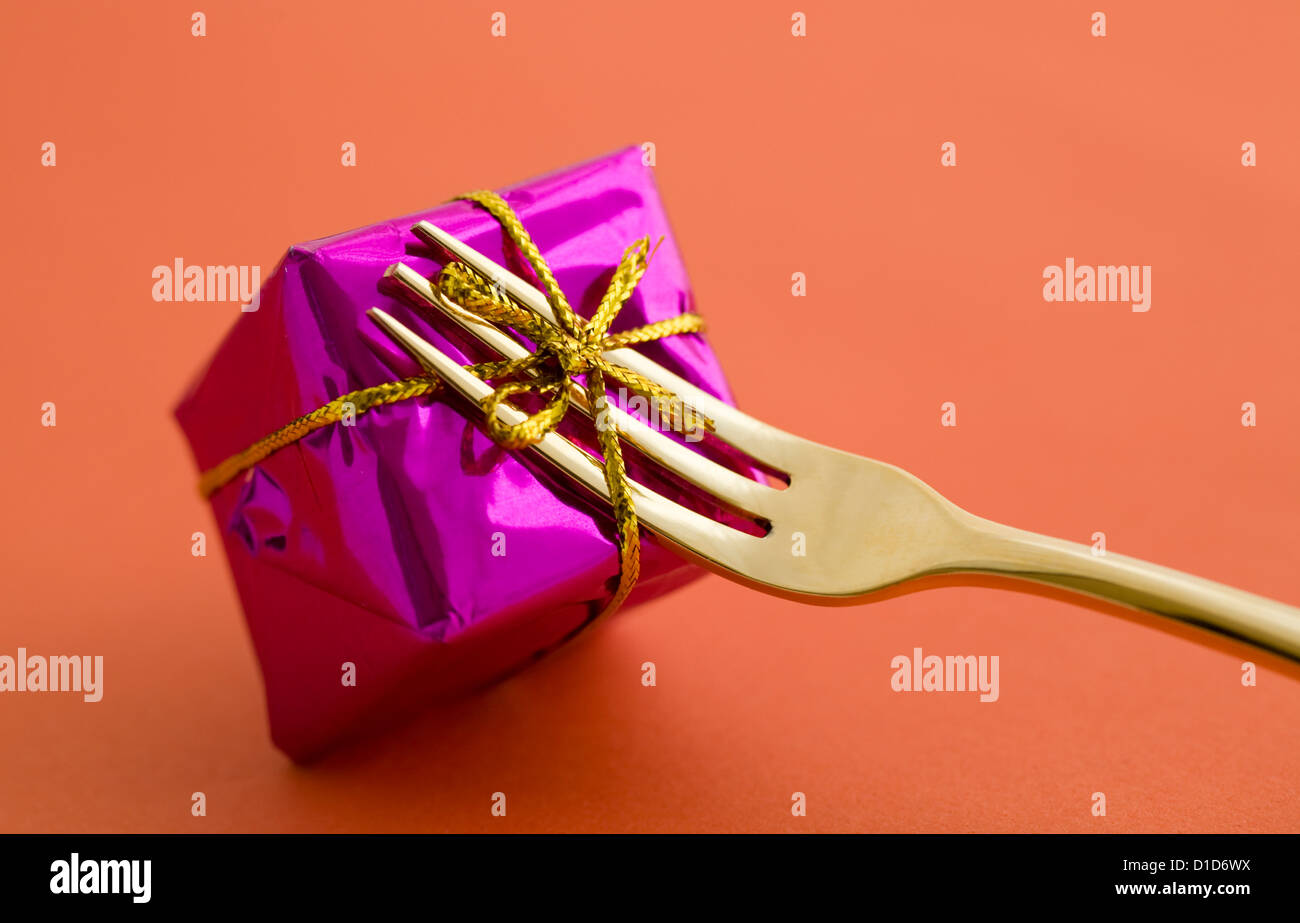 Pink wrapped gift parcel with a golden fork Stock Photo - Alamy