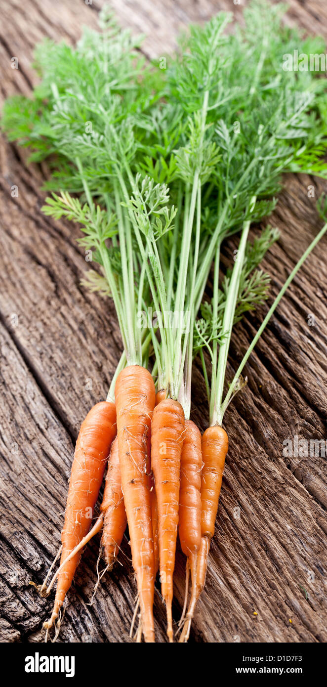 Carrots with leaves on a old wooden table Stock Photo - Alamy