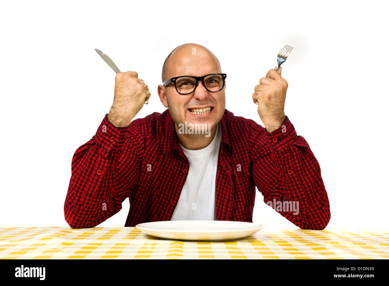Young adult bold man sitting at the dinner table with fork and knife ...