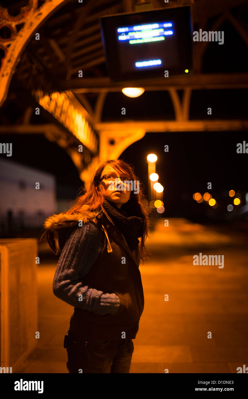 A young woman teenage girl person alone on a deserted railway station ...