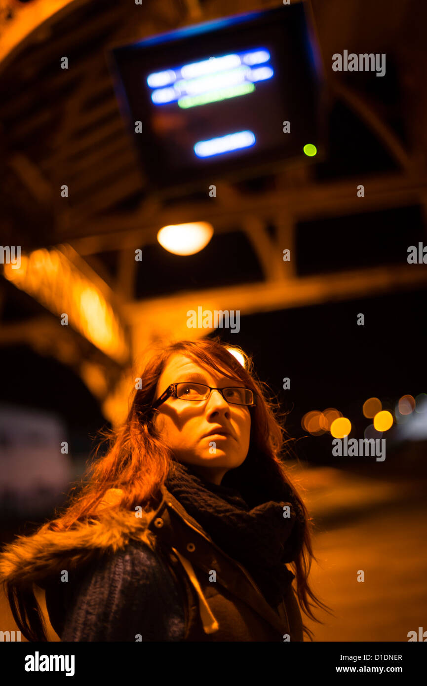 A young woman teenage girl person alone on a deserted railway station ...