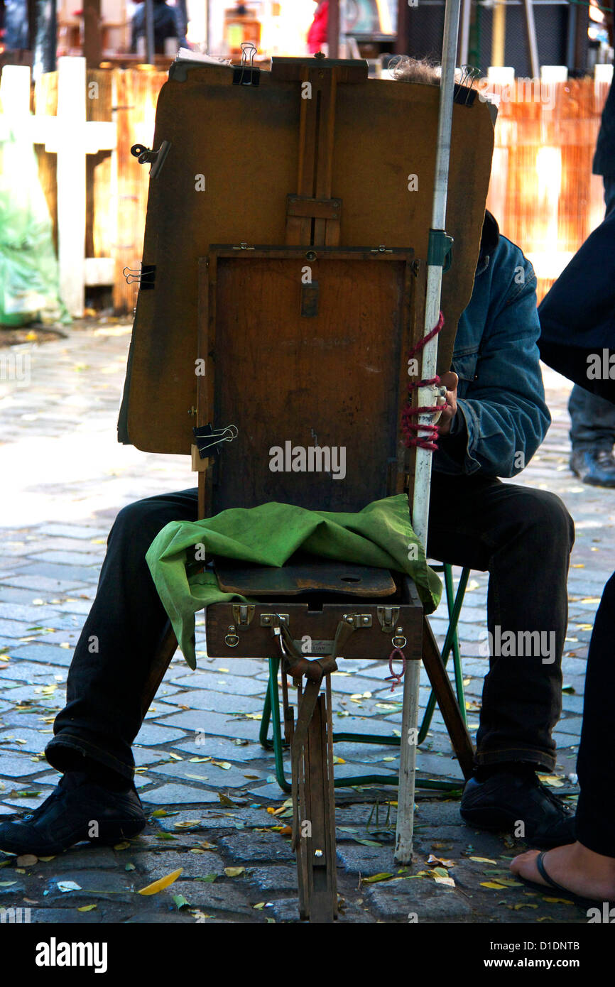 Artist working on a portrait his face hidden behind easel Place du ...