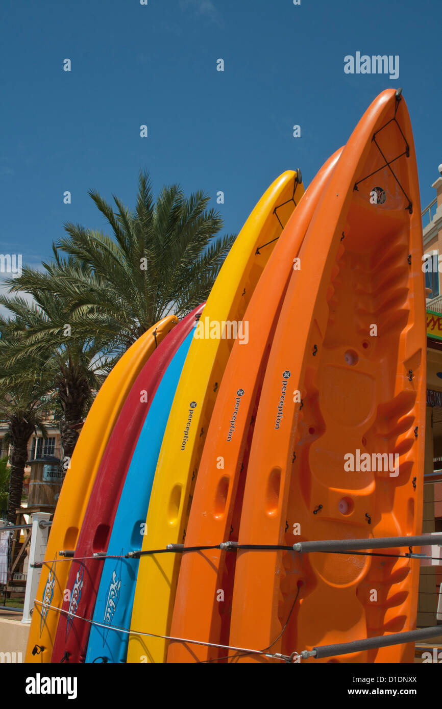 Kayaks stacked in colorful array against blue sky and green palm trees ...