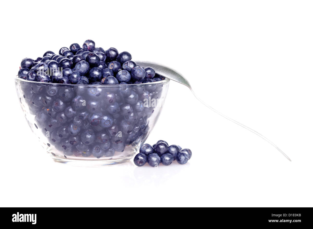 Blueberries in transparent glass dish with soft shadow and spoon on ...