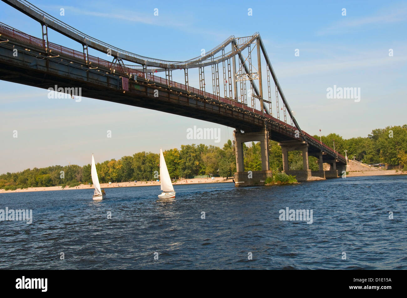 Two small vessel ships under a big metal bridge and beach on background ...