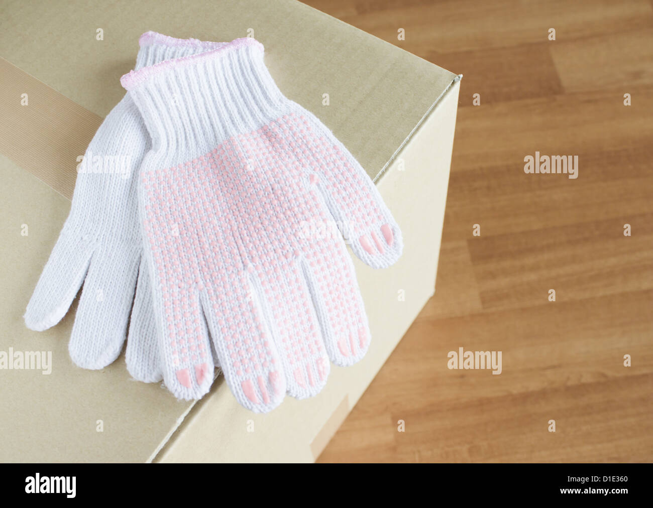Cardboard box and work gloves on a wooden floor Stock Photo - Alamy